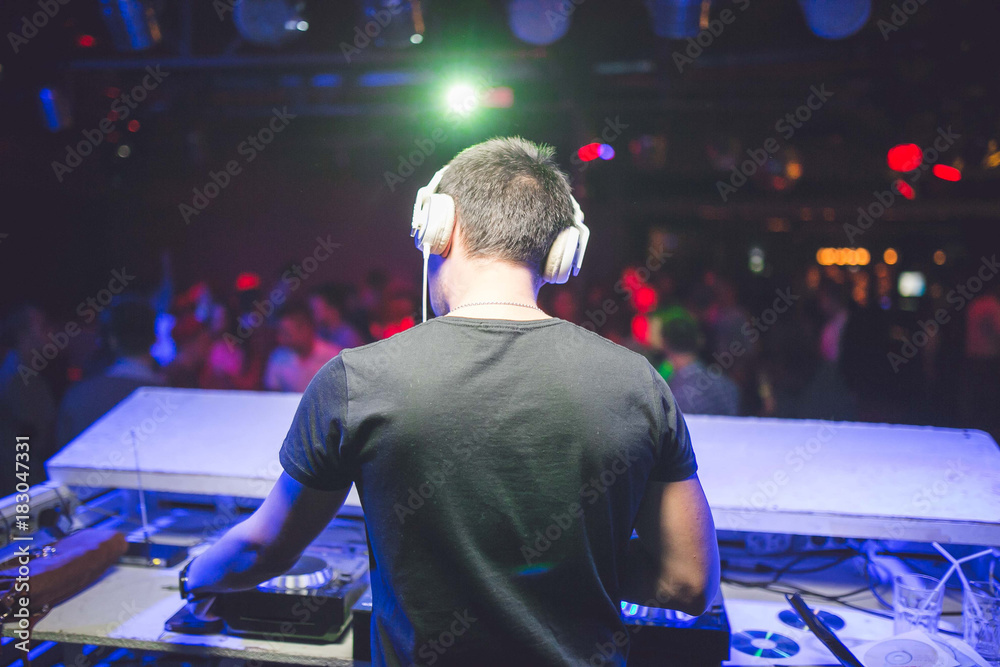 Dj at work in luxury nightclub during night party with many audience at ...