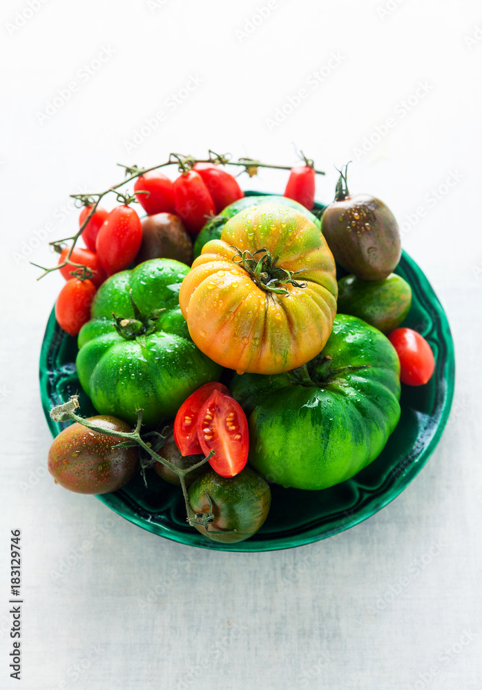 different kinds, types and color of tomatoes on a white stone table ...