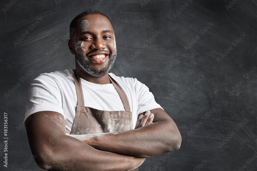 Portrait of cheerful dark skinned black male chef has pleasant smile ...