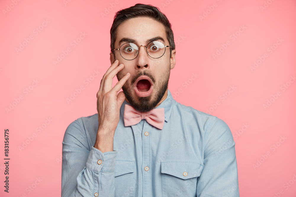 Shocked young handsome man stares through spectacles, being surprised ...
