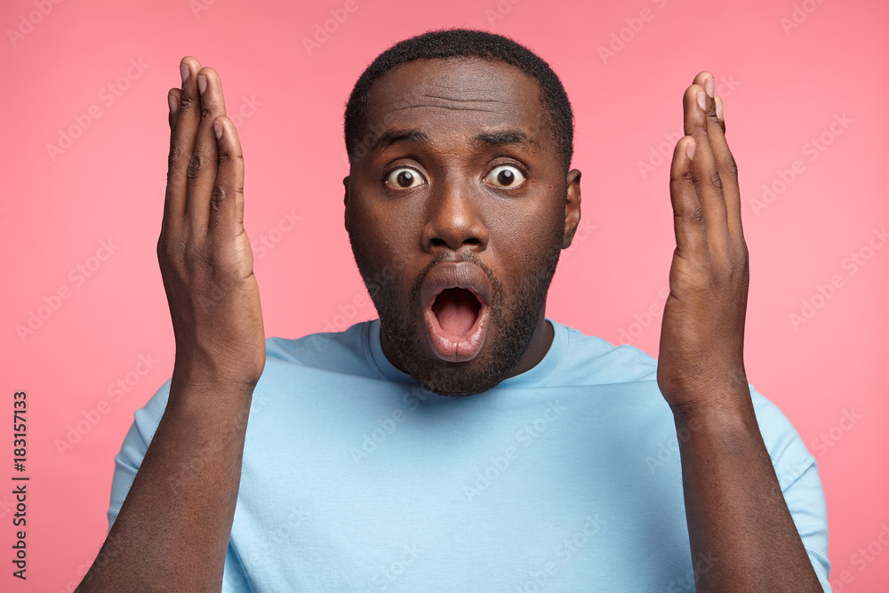 Frightened bugged eyed black man gestures actively, keeps mouth widely ...