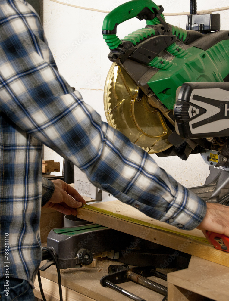 Craftsman measuring a piece of wood to cut it to size on the miter saw ...