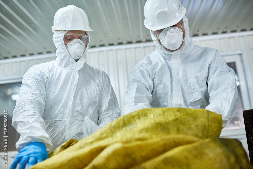 Low angle portrait of two workers wearing biohazard suits working at ...