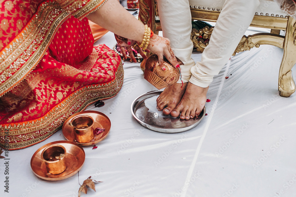 Woman covers groom's feet with a water during Hindu wedding ceremony ...