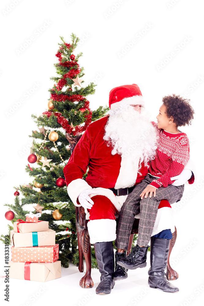 Mixed race little boy talking with Santa Claus sitting on his lap near ...