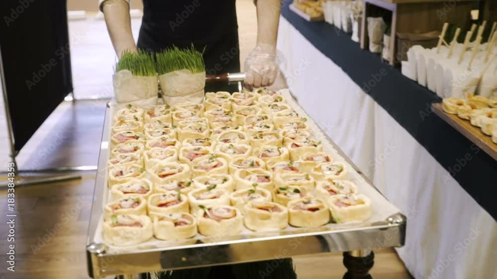 trolley on wheels to serve food on the dining table. The waiter takes ...
