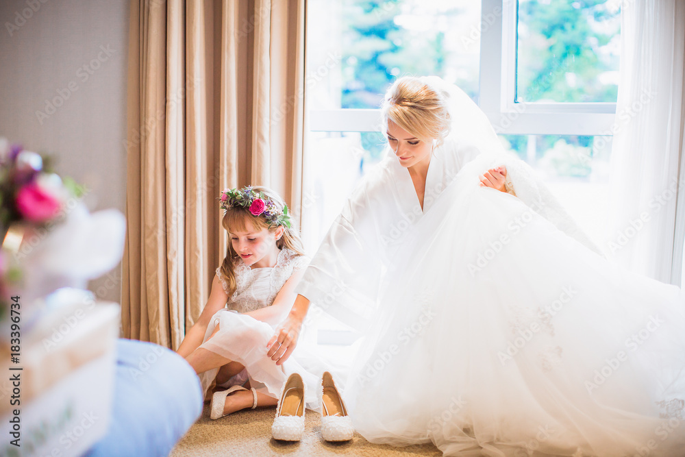 The beautiful little girl sitting on the floor near window with ...