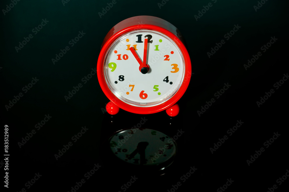 Red alarm clock with time shows 11 o'clock with reflections on an ...