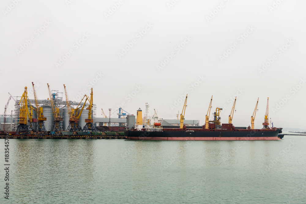 Port terminal of bulk cargo. Port elevator with loading vessel. Stock ...