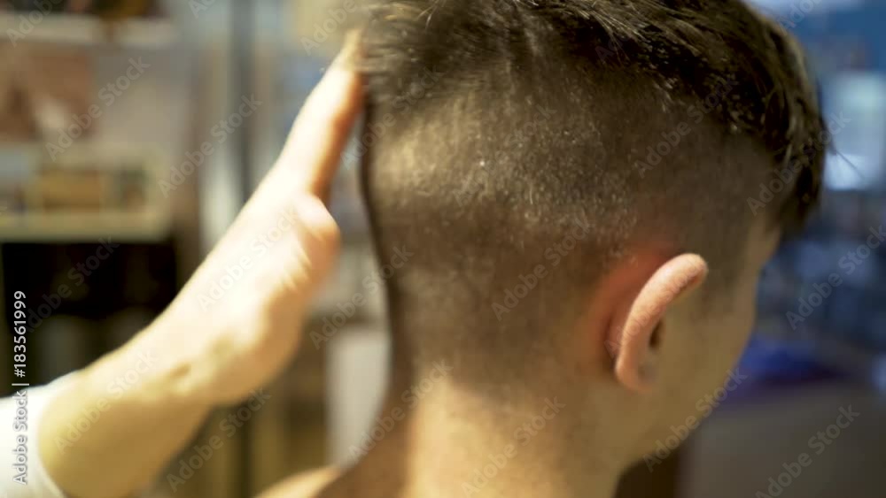 Closeup of teenage boy using a trimmer to cut his hair very short on ...