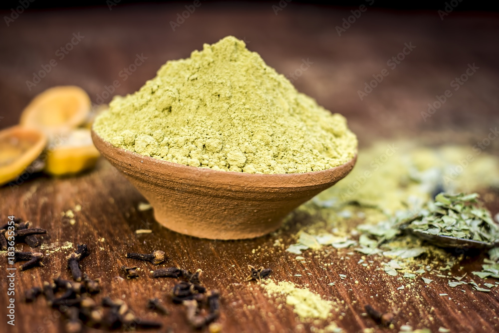 Raw powder of Henna,Lawsonia inermis in a clay bowl with lemons and ...