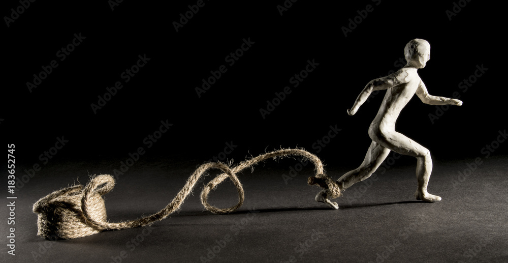 Man tries to run away with a rope tied to the foot. Concept of hope ...