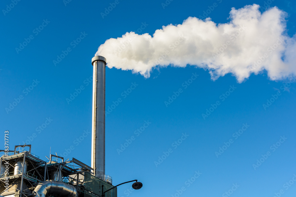 Smoking factory chimney. The tall metallic smokestack of an ...