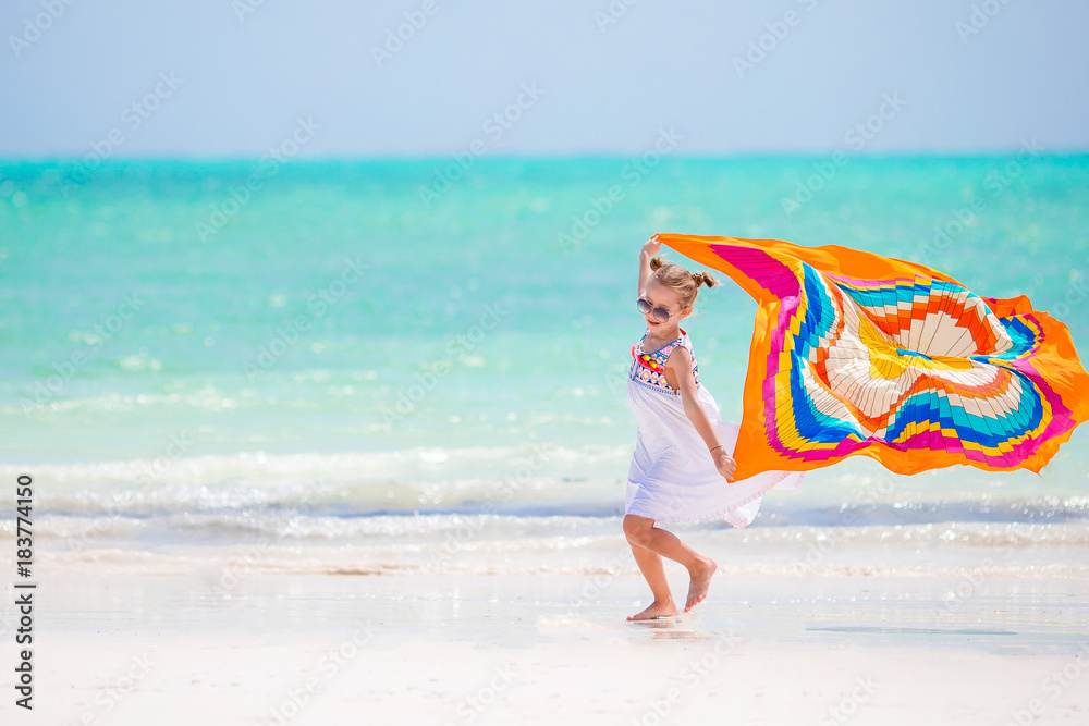Happy little girl having fun running with pareo on tropical white beach ...