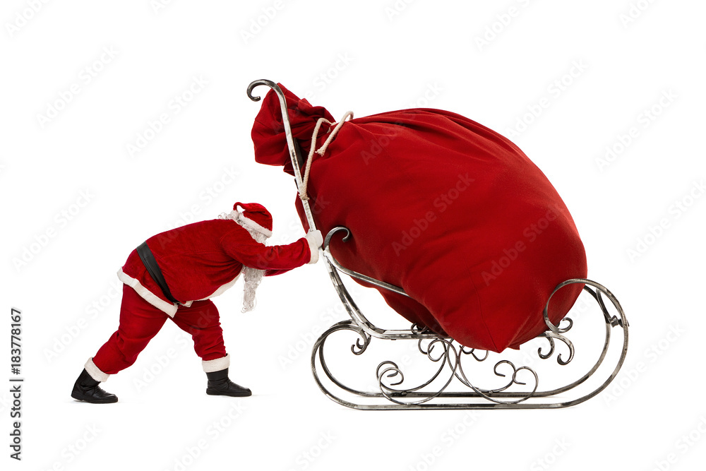 Santa Claus pushing sleigh with huge bag full of christmas gifts ...