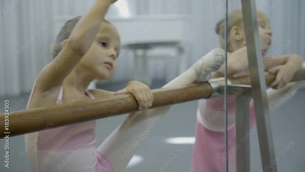 Two little girls do dance exercises on ballet machine. Children in ...