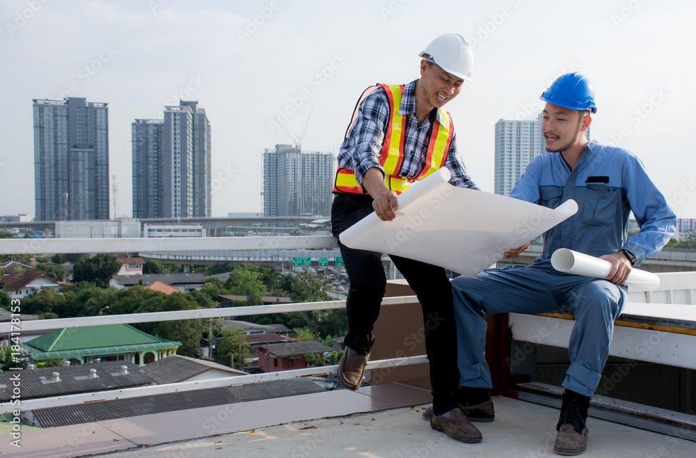 Foto de Engineers and foreman wearing safety helmet hold blueprint talking about construction ...
