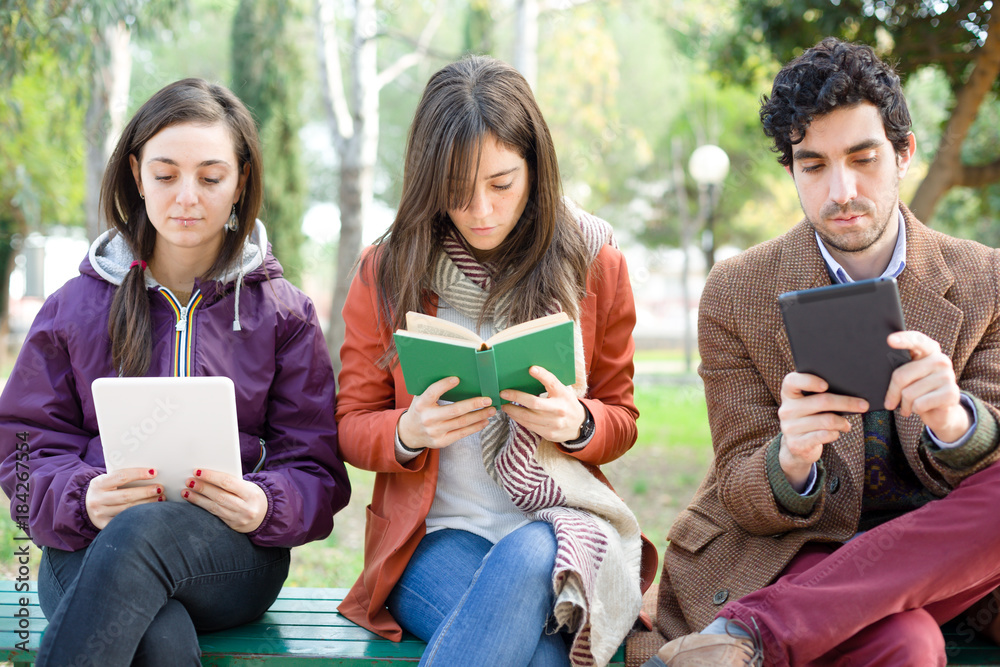 One Woman Sitting on a Bench in a Park Reading a Paper Book with Two ...