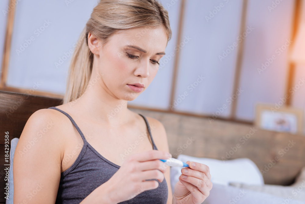 Unbearable sickness. Fair-haired young woman sitting in her bed and ...