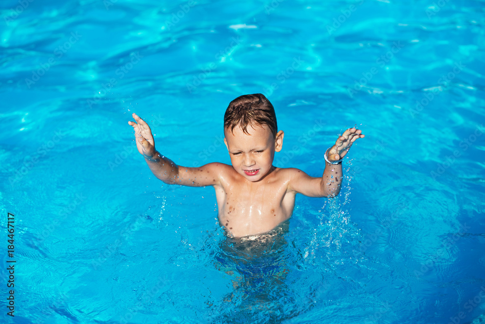Happy kid playing in blue water of swimming pool. Little boy learning ...