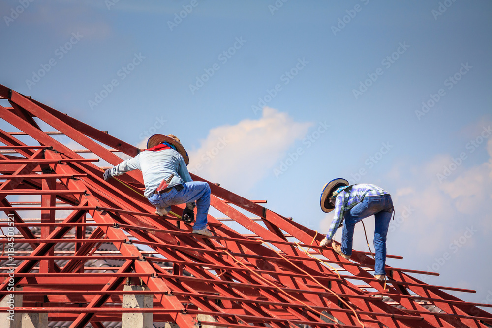 welder workers installing steel frame structure of the house roof at ...