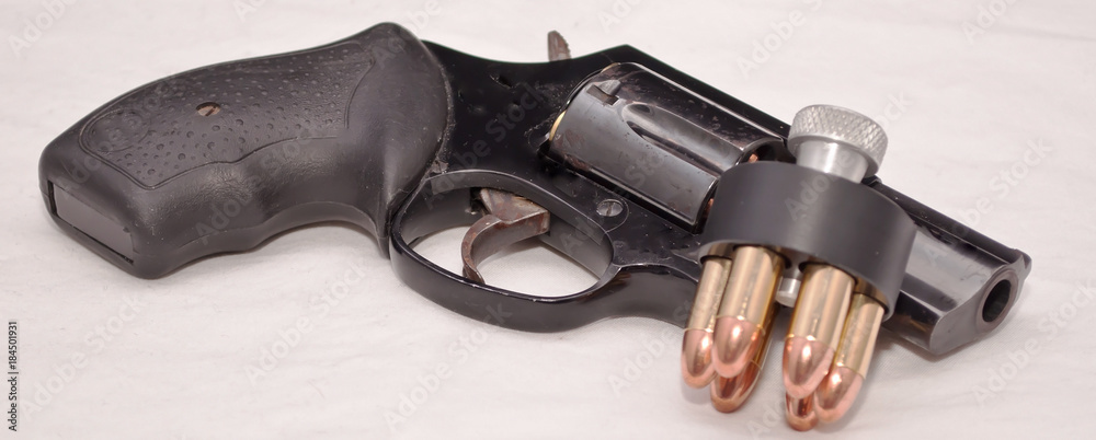 A black revolver with a loaded speed loader leaning against the barrel ...