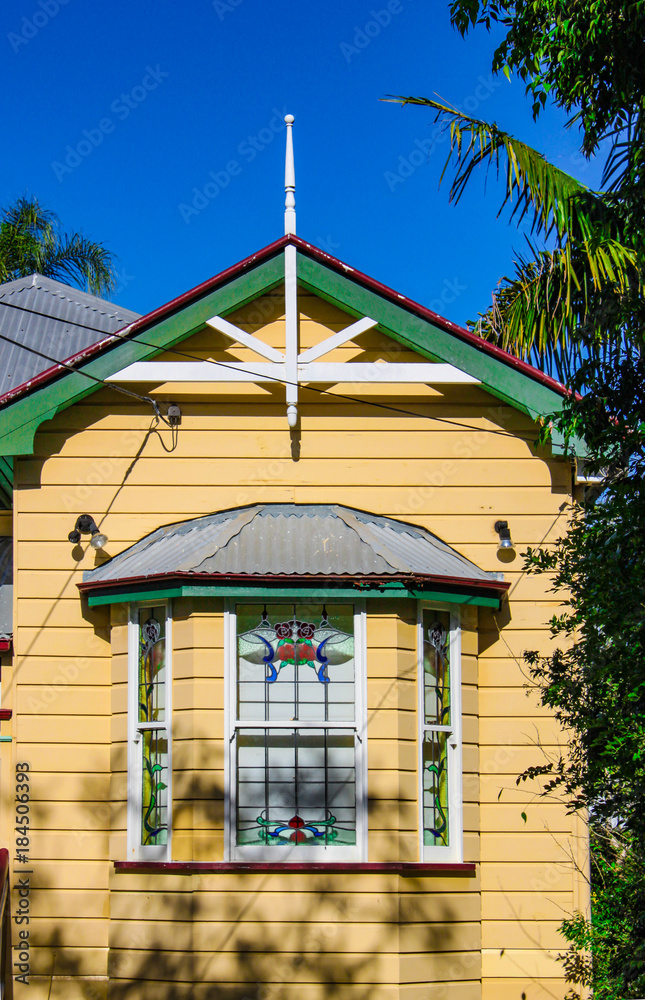 Bay window on yellow traditional Australian Queenslander House with tin ...