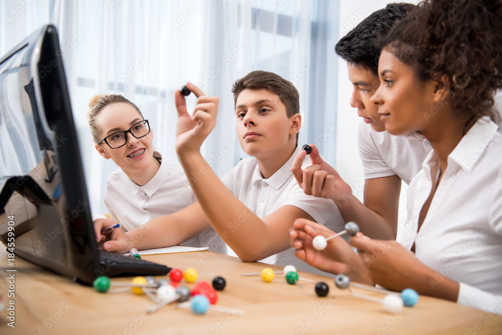 young multicultural students picking molecular model for science lesson ...