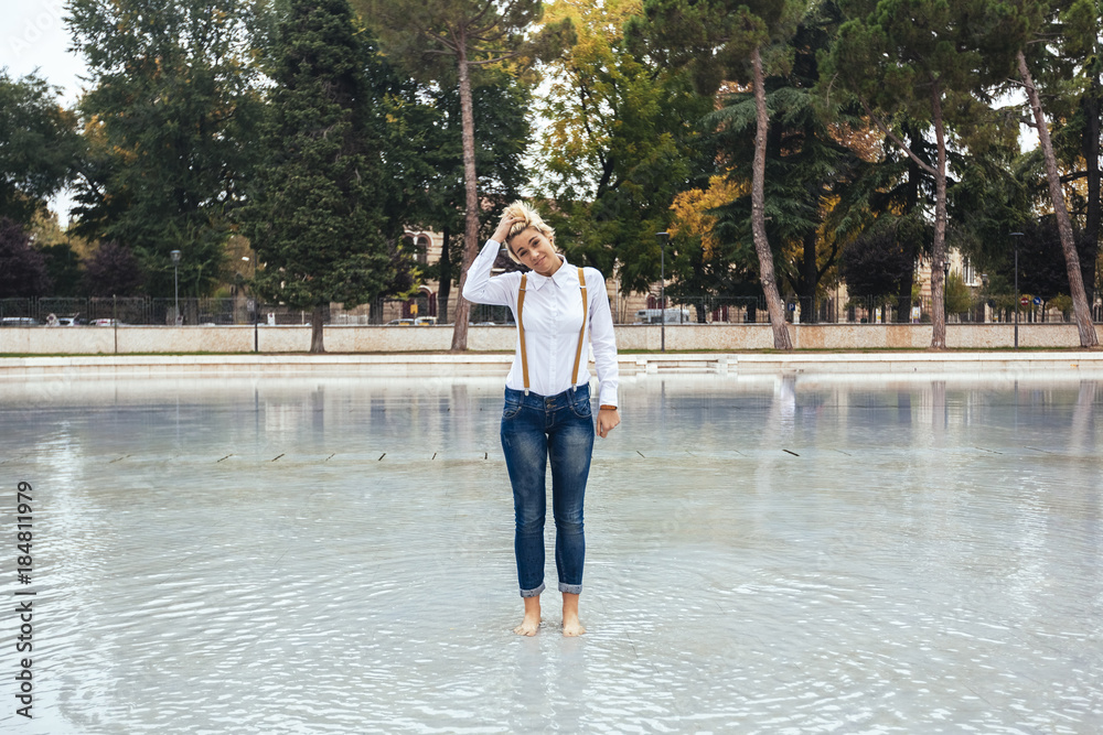 Teenage girl standing barefoot in pool, looking confused Stock Photo ...