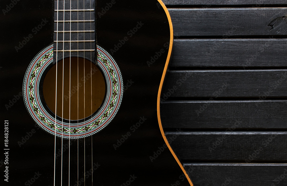 Black Acoustic Guitar body closeup, vertical, on a black wood table ...