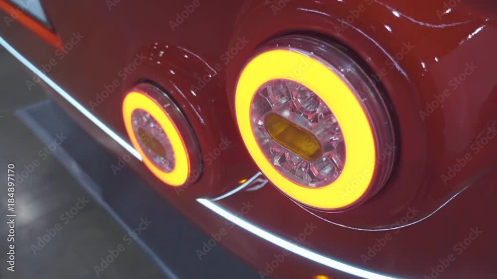 The beautiful rear lights of the red car burn yellow. Twin rear wheels ...