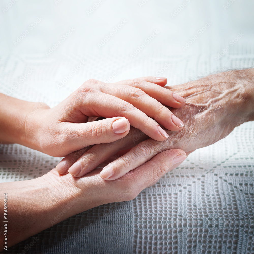 Old and young holding hands on light background, closeup. Care is at ...