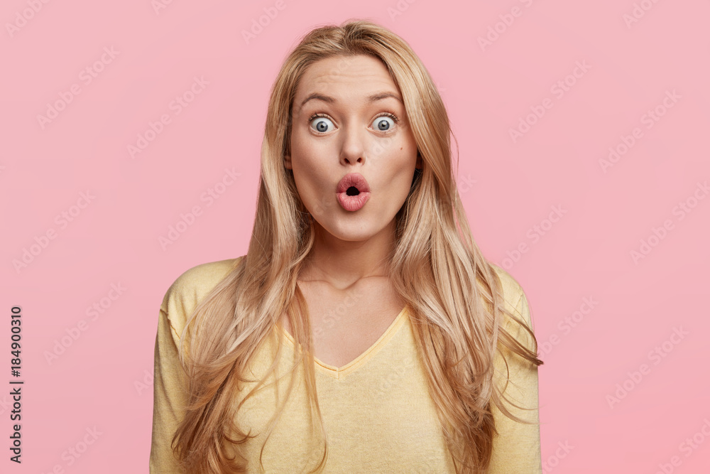 Puzzled shocked female looks with bugged eyes at camera, being ...