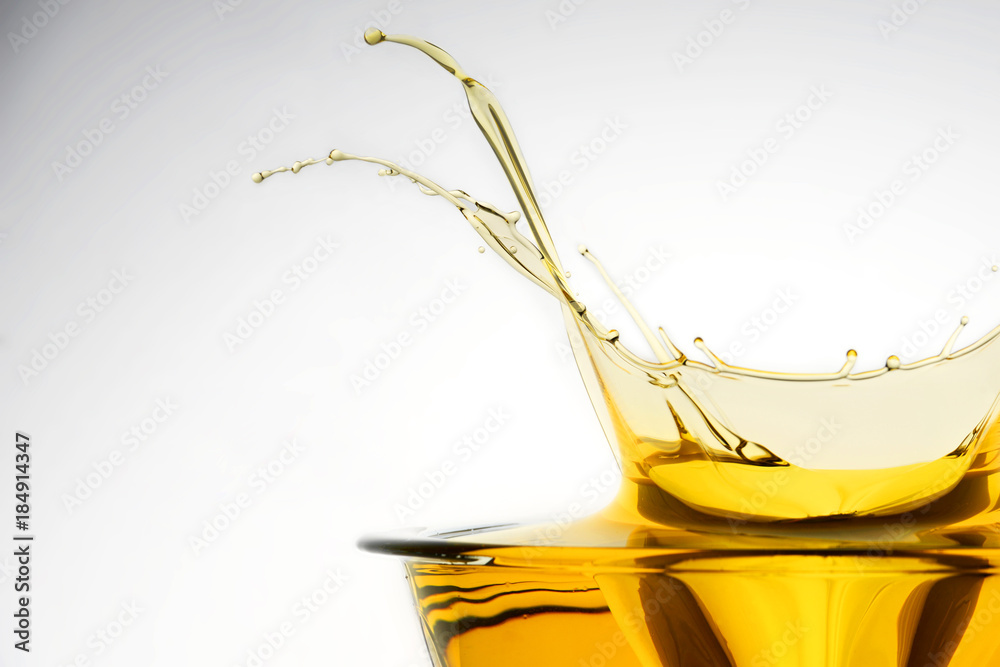 Side view of cooking oil splashing in container, studio background ...