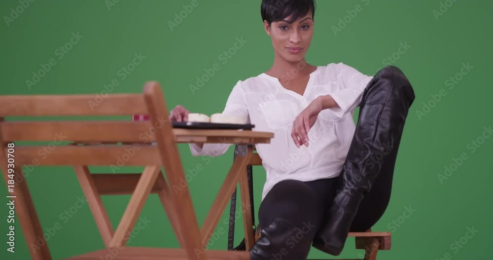 Young black woman in boots poses sensually with her ipad at a caf ...