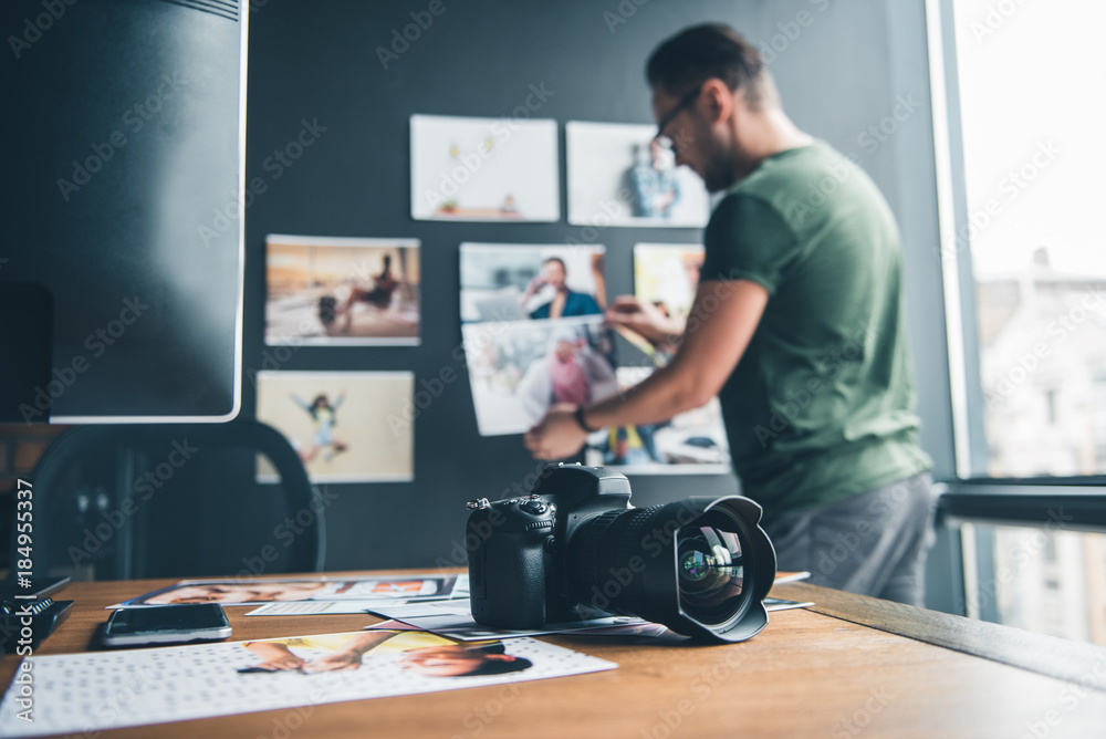 Focus on camera and photos locating on desk in office. Side view ...