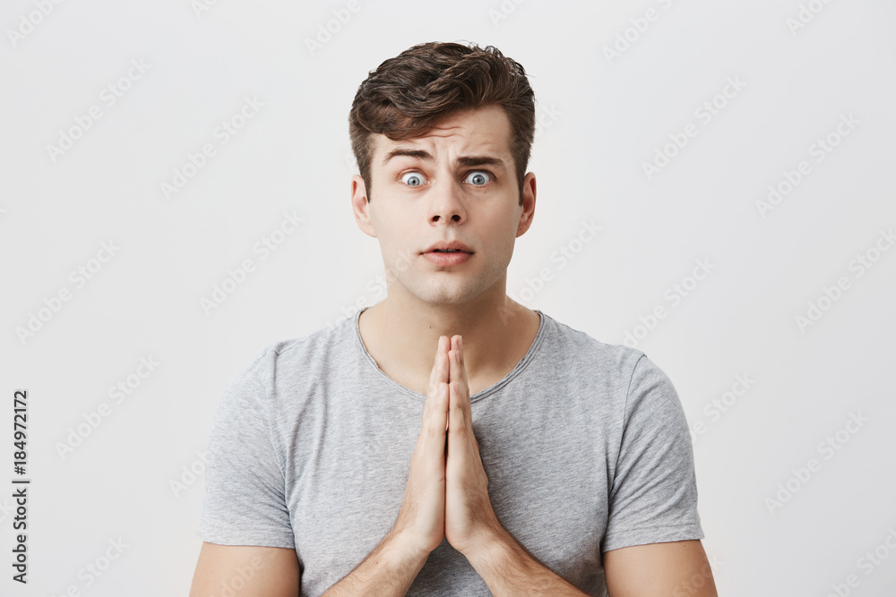 Attractive trendy guy with dark hair holding hands at his face ...