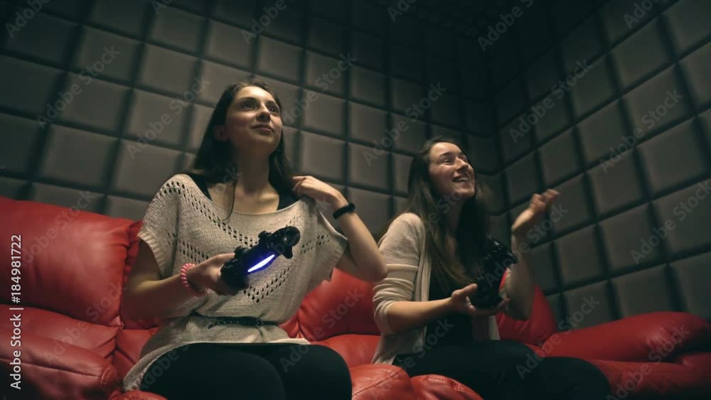 Two Young Girls Playing Video Games With Game Controller On Red Sofa 5590