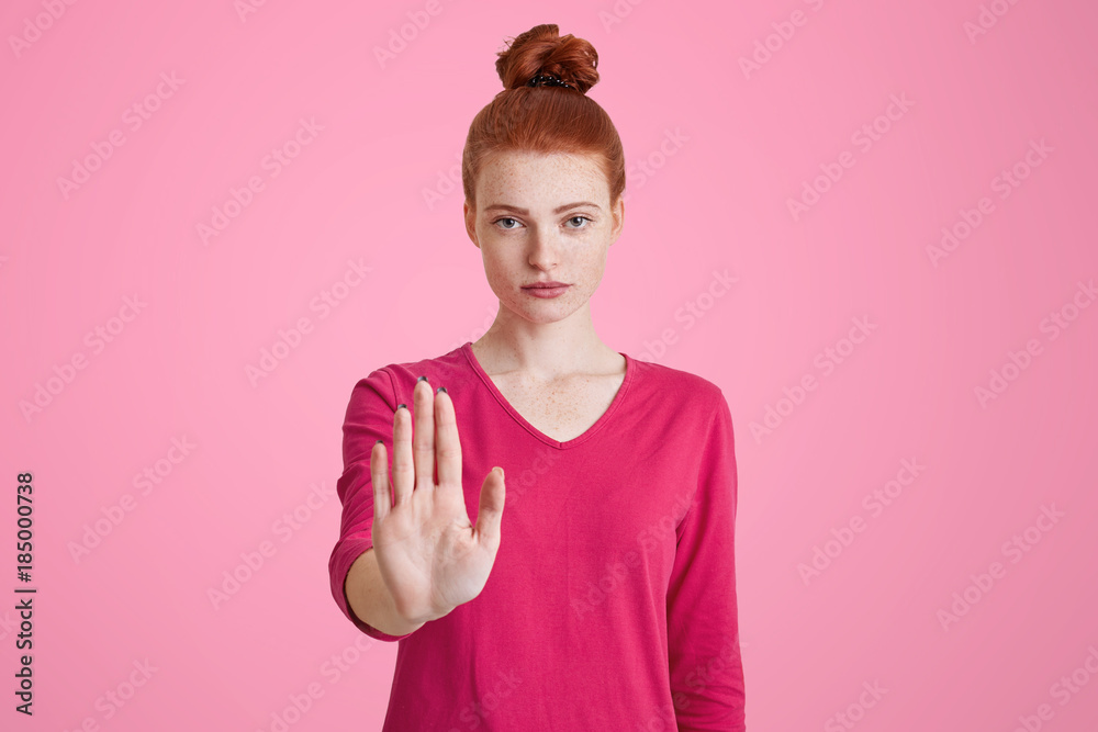 Prohibition symbol. Young attractive freckled female gestures in studio ...
