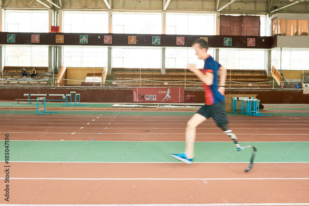 Blurred motion of amputee athlete running on track of indoor stadium ...