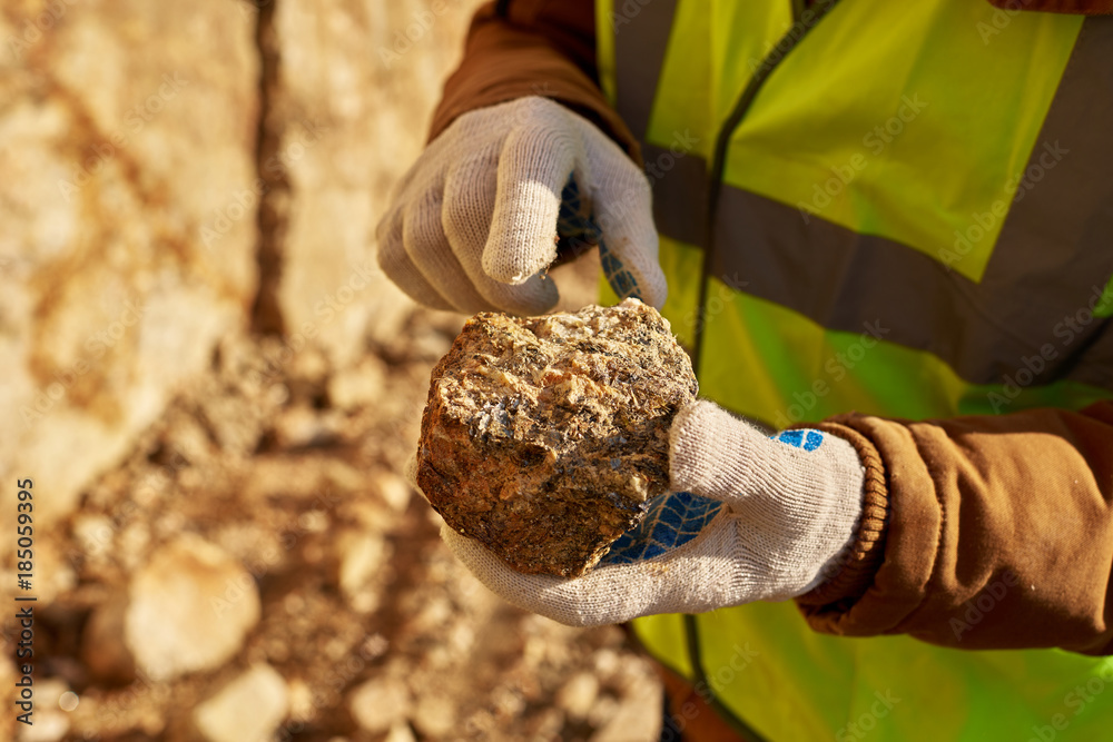 Close up of industrial worker holding mineral ore in gloved hands on ...