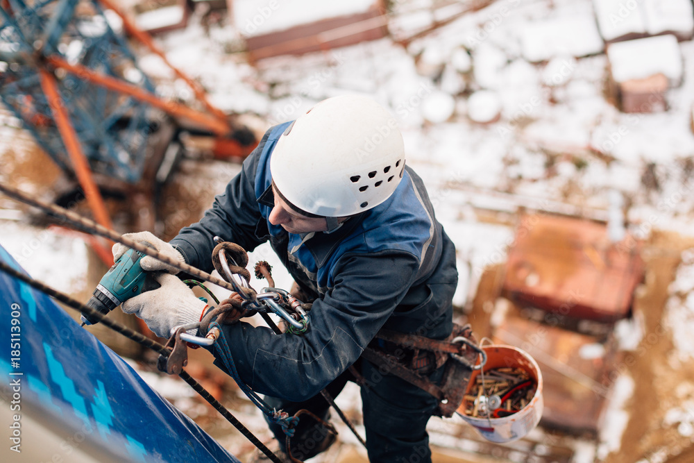 Professional industrial climber in helmet and uniform works at height ...