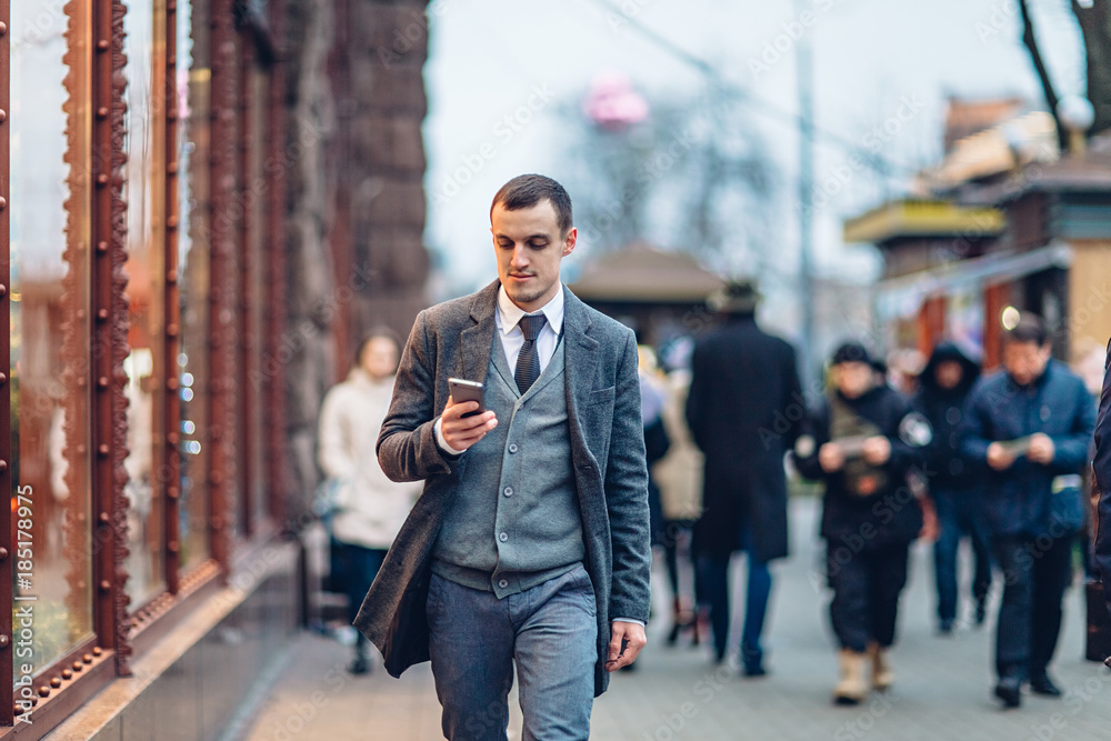 Young man using the phone while walking along the street Stock Photo ...