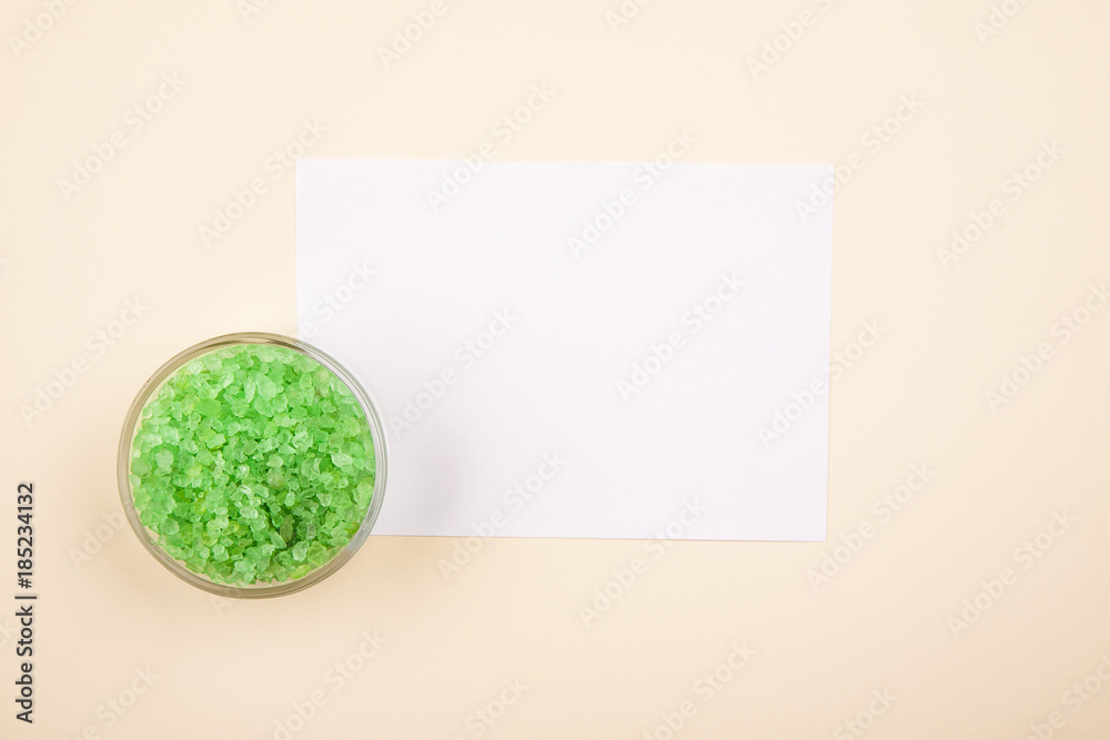 Green sea salt in a glass container with blank white paper card ...