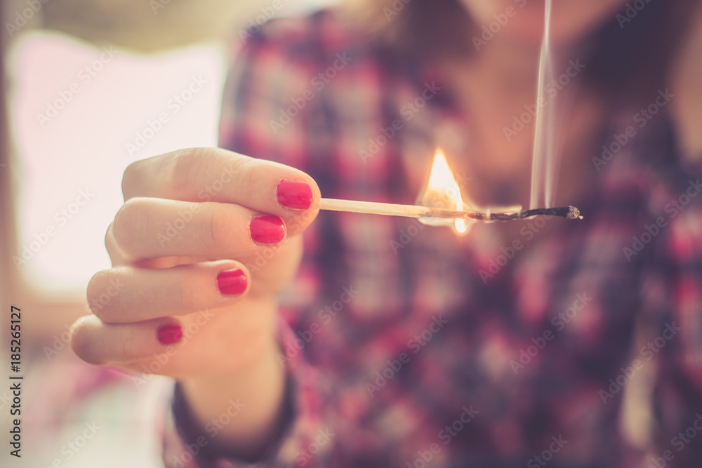Junge Frau mit roten Fingernägeln hält brennendes Streichholz in der Hand Stock-Foto | Adobe Stock