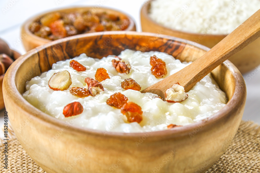 Rice milk porridge with nuts and raisins in wooden bowls on a white ...