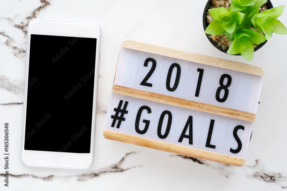 2018 goals on wood box and smart phone with blank on screen at office ...