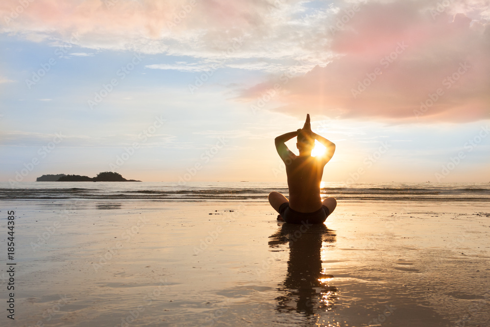 Zen-like idyllic scene. Young man meditating on sunset sea beach in ...