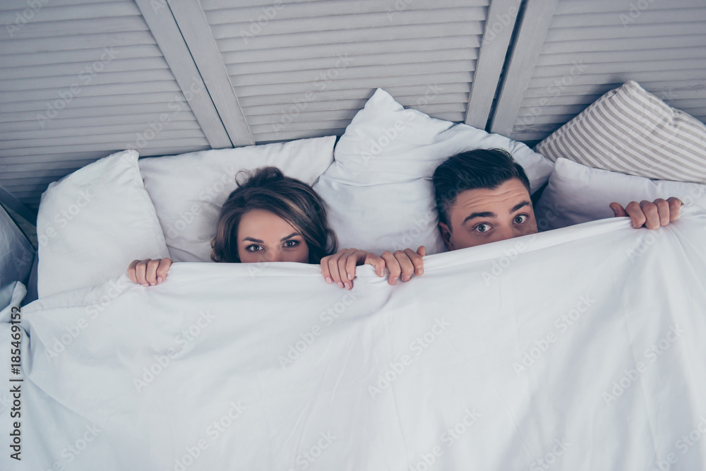 Top view of beautiful funny partners hiding behind blanket, peeking ...