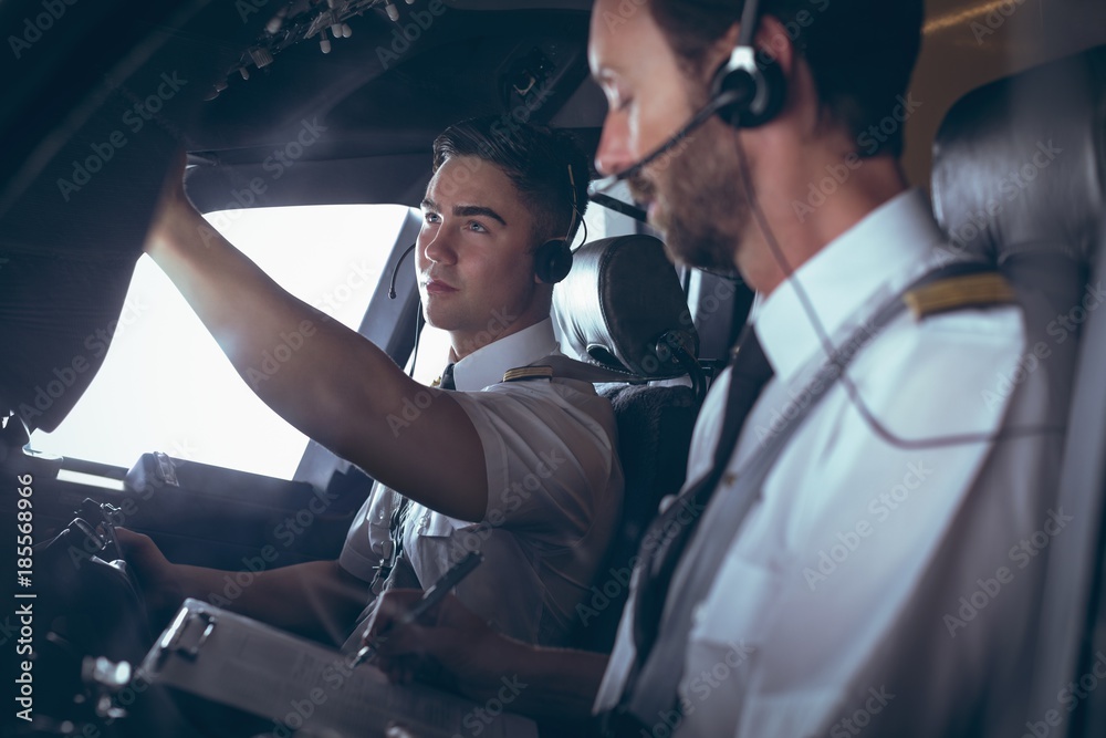 Pilot flying an airplane while copilot writing on clipboard Stock Photo ...